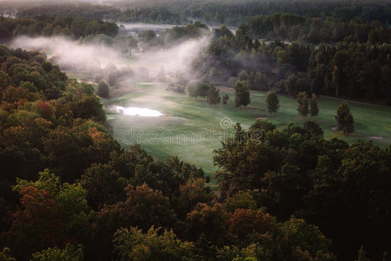 Aerial Shot of a Golf Course with a Small Pond Surrounded by a Dense ...