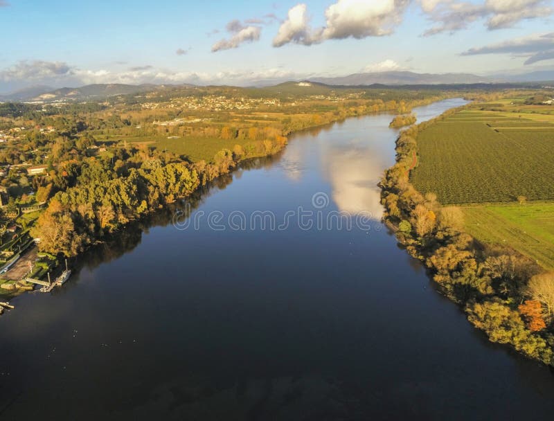 Aerial Shot of a River with Reflection of Clouds and Green Fields on ...