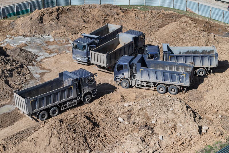 Aerial Top View of Several Dump Trucks Unloading Sand at a Construction ...