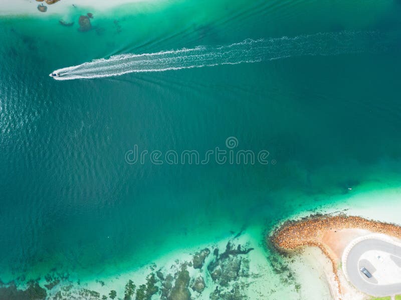 Aerial View of a Boat Navigating a Picturesque Lake, Leaving a Trail of ... Aerial View of a Boat Navigating a Picturesque Lake, Leaving a Trail of ...