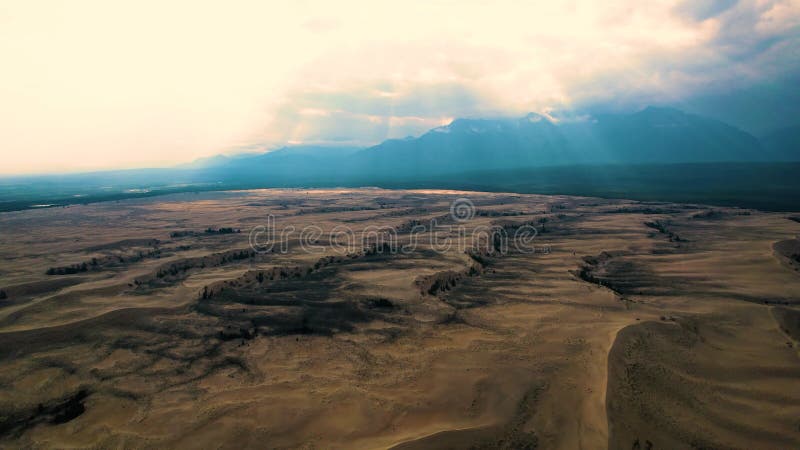 Aerial View of Desert Landscape with Distant Mountains and Sun Rays ...