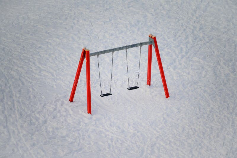 An Aerial View of an Empty Swing Set with Red Legs Surrounded by Snow ...
