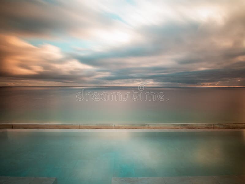 A Long Infinity Pool with Palm Trees and Ocean Views in a Sunny Resort ...