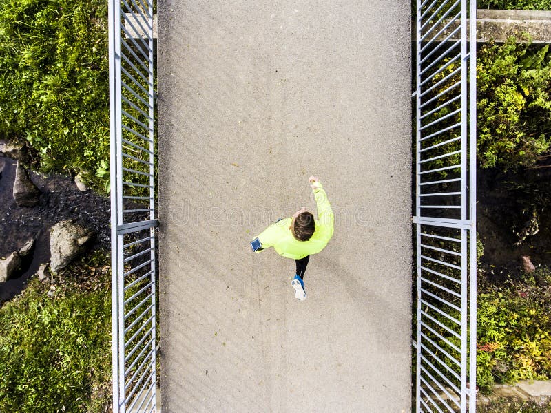 Aerial View of a Runner Running Across Bridge in Park on a Jogging Path ...