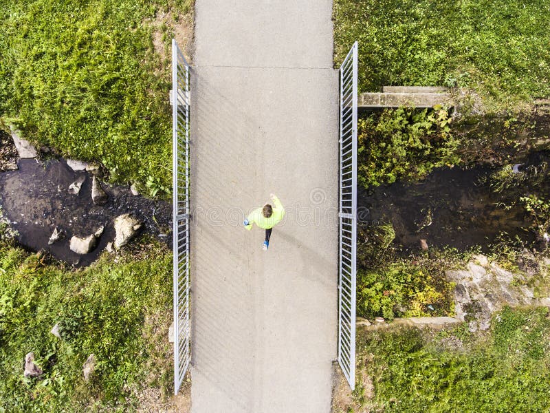 Aerial View of a Runner Running Across Bridge in Park on a Jogging Path ...