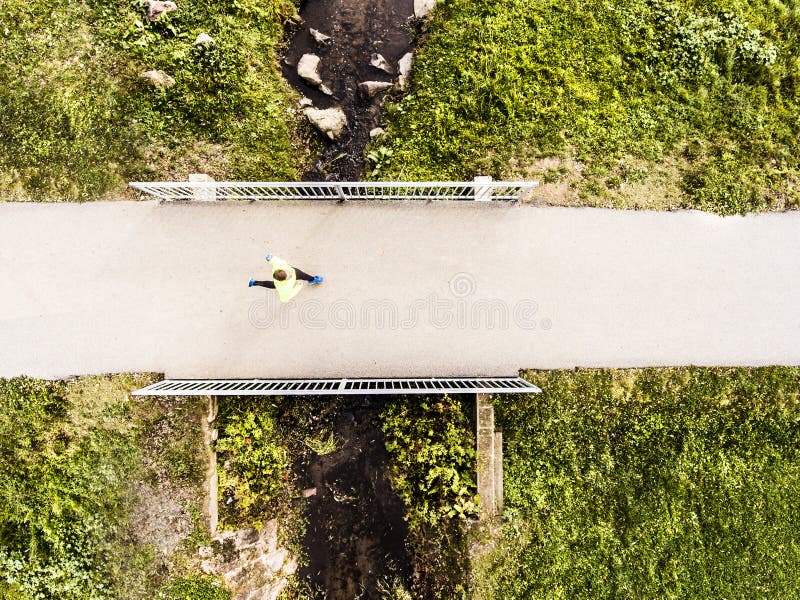 Aerial View of a Runner Running Across Bridge in Park on a Jogging Path ...