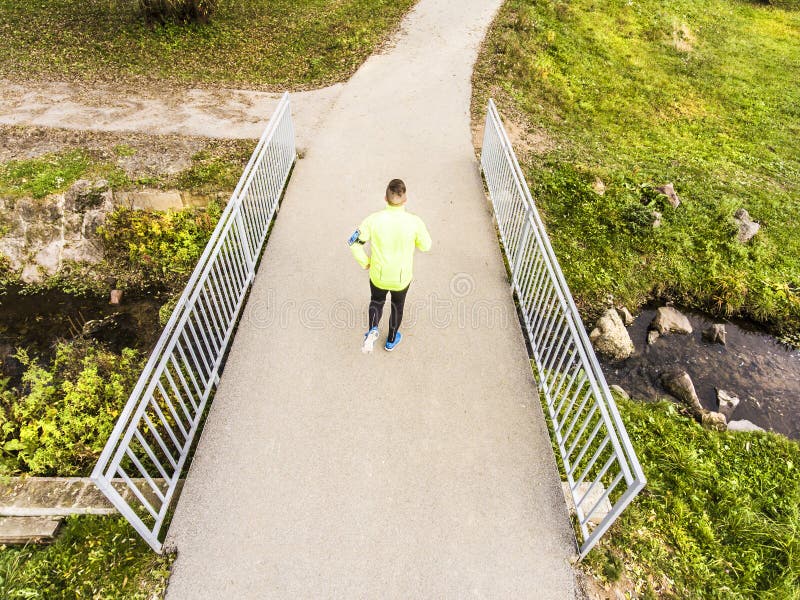 Aerial View of a Runner Running Across Bridge in Park on a Jogging Path ...