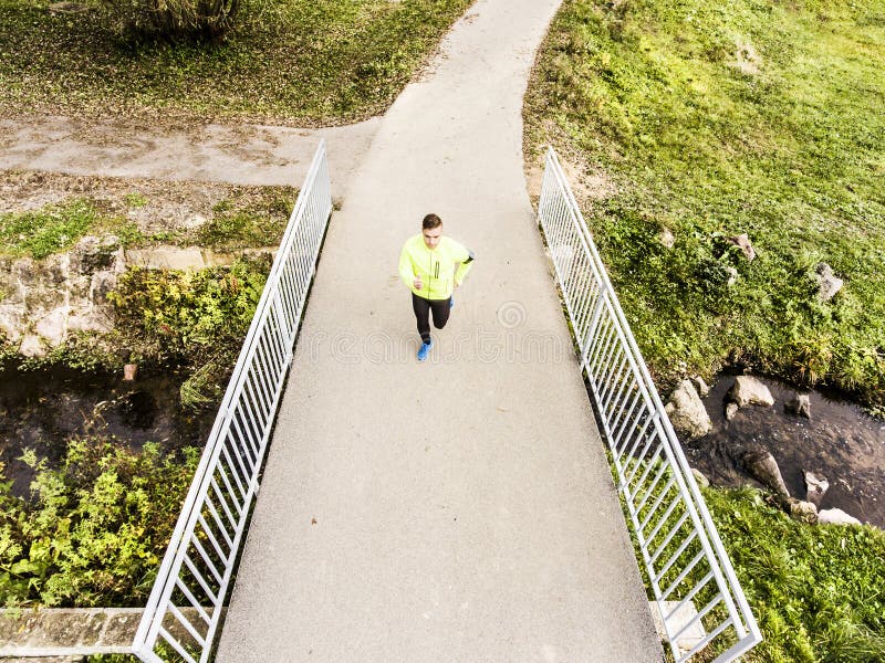 Aerial View of a Runner Running Across Bridge in Park on a Jogging Path ...