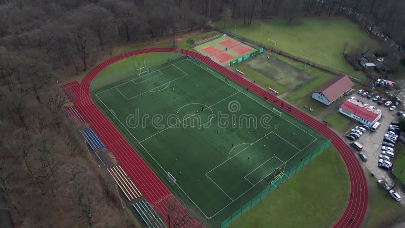 Aerial View of Stadium in Small Town, Players Play Football on Soccer ... Aerial View of Stadium in Small Town, Players Play Football on Soccer ...