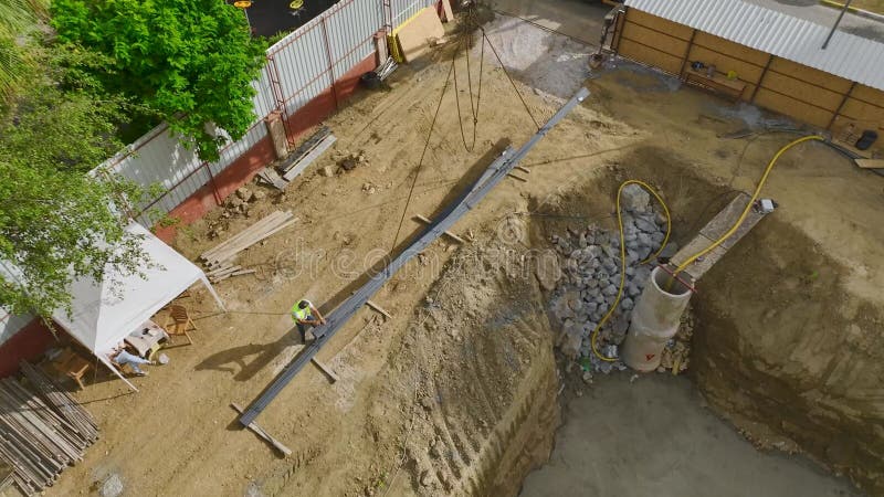 Aerial View: Workers Pour Concrete into a New Foundation, Guided by Engineers Ensuring ...