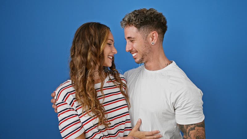 Affectionate Couple Laughing Together Against a Solid Blue Background ...