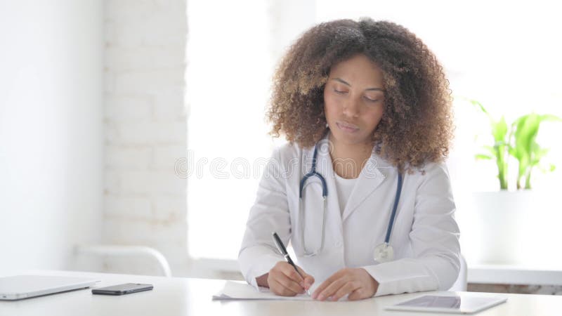 Afrcian Doctor Thinking while Writing on Paper in Clinic Stock Image ...