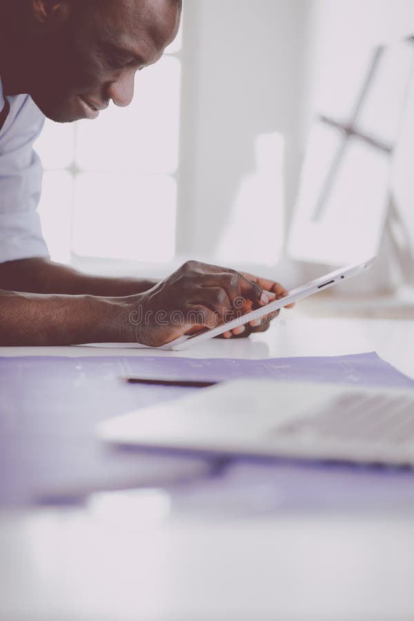 African American Architect Working with Computer and Blueprints in ...
