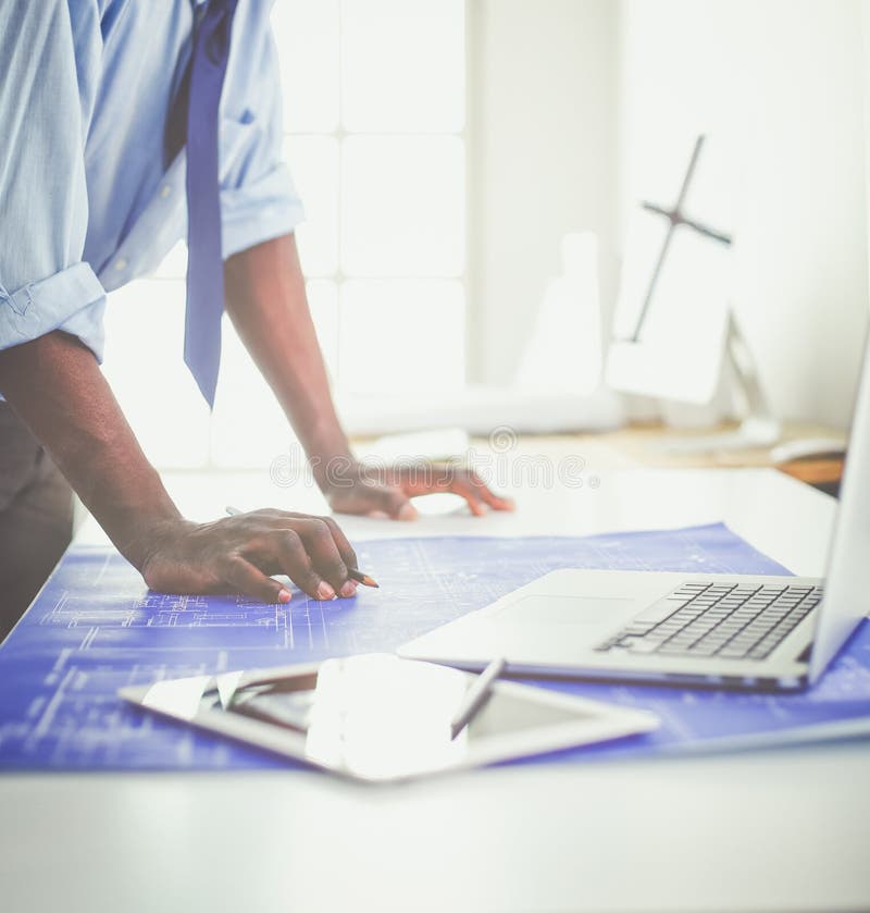 African American Architect Working with Computer and Blueprints in ...