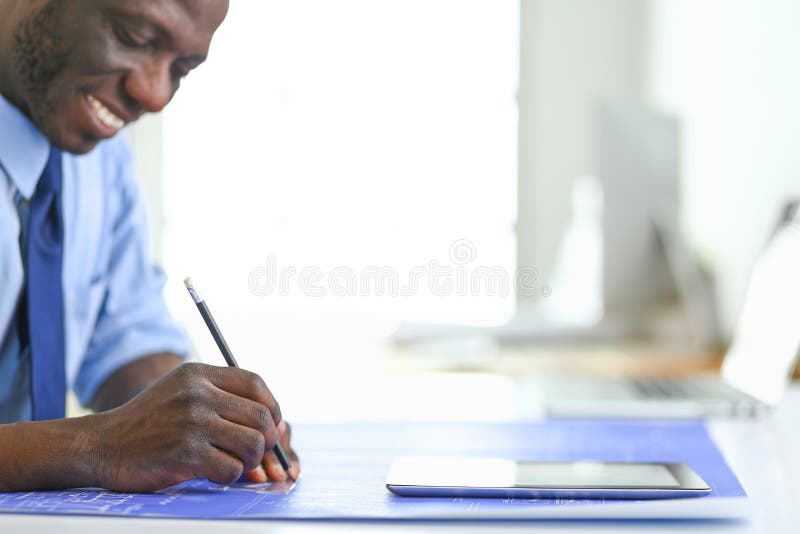 African American Architect Working with Computer and Blueprints in ...