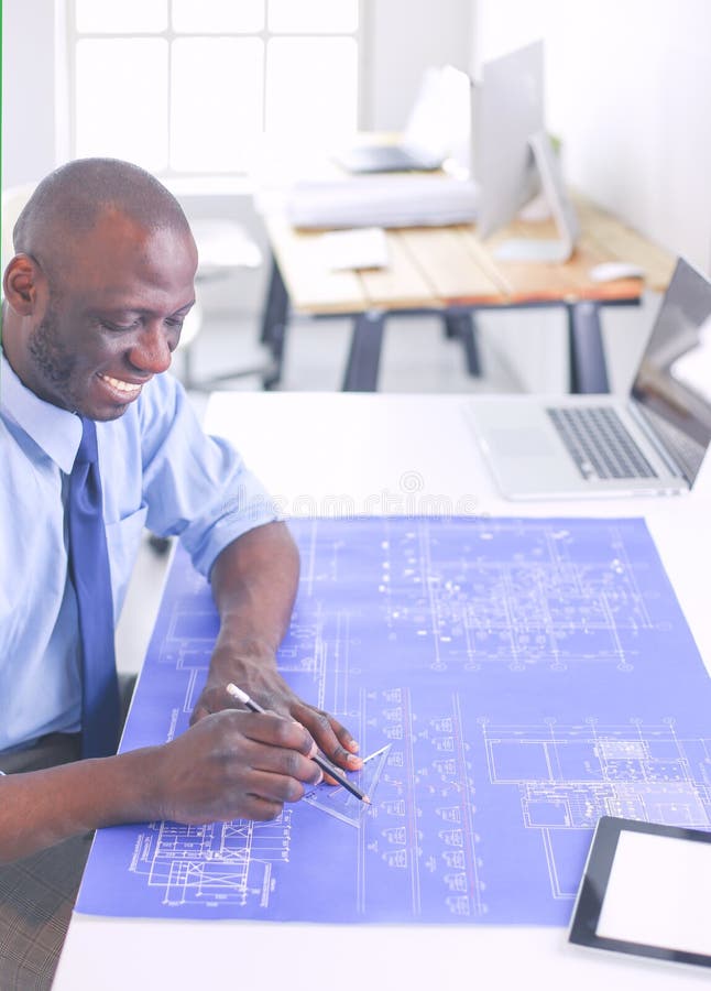 African American Architect Working with Computer and Blueprints in ...