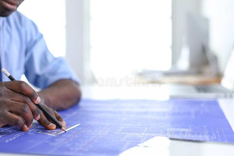 African American Architect Working with Computer and Blueprints in ...