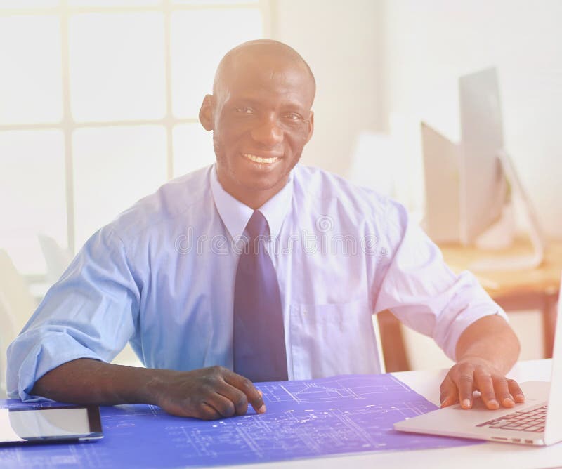 African American Architect Working with Computer and Blueprints in ...