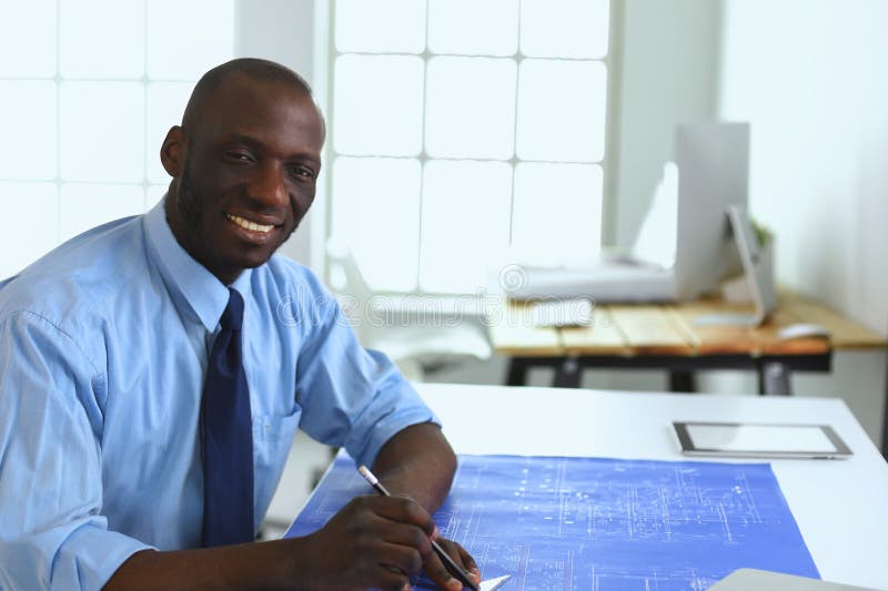 African American Architect Working with Computer and Blueprints in ...