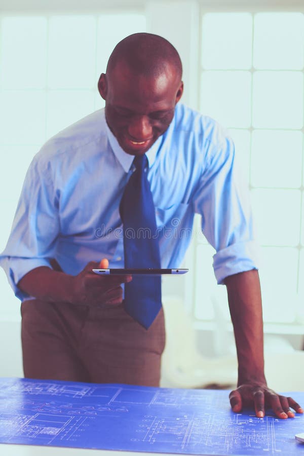 African American Architect Working with Computer and Blueprints in ...