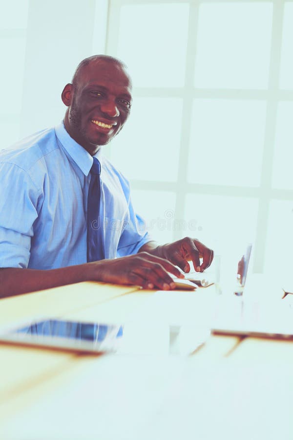 African American Architect Working with Computer and Blueprints in ...