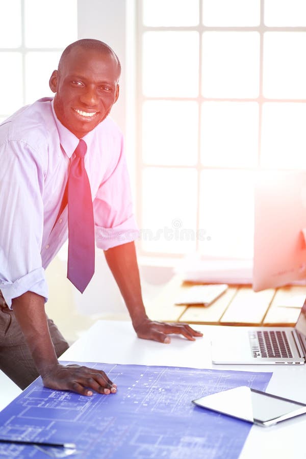 African American Architect Working with Computer and Blueprints in ...