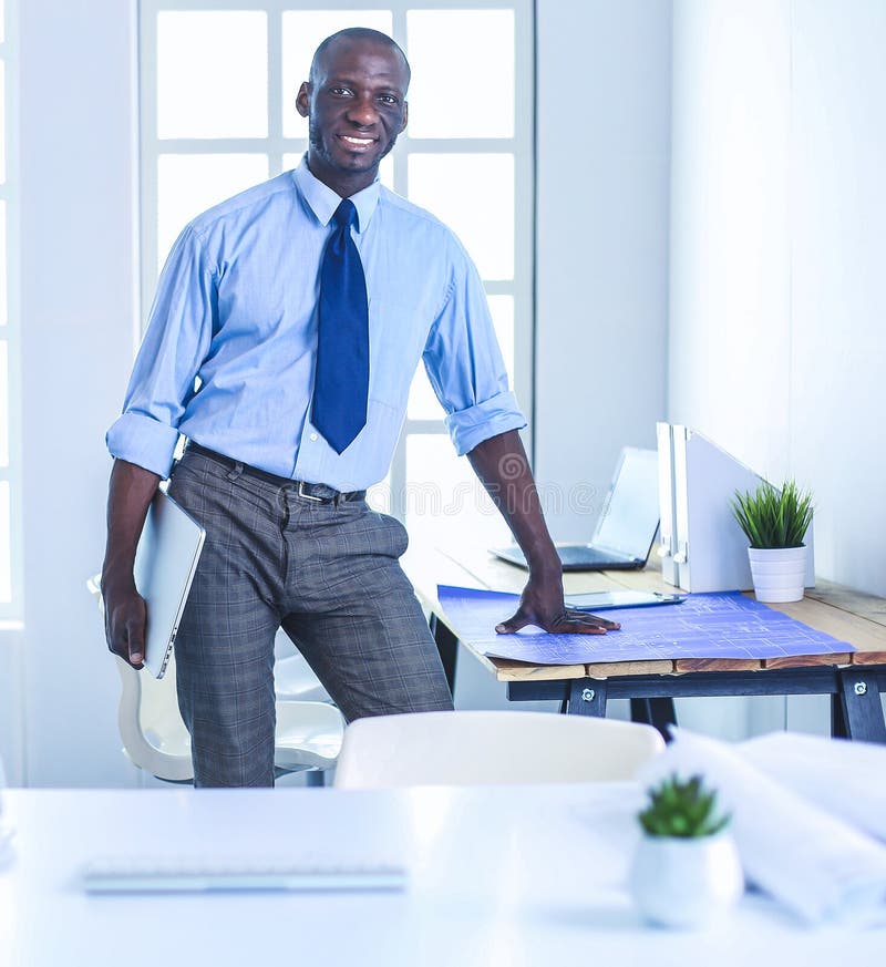 African American Architect Working with Computer and Blueprints in ...