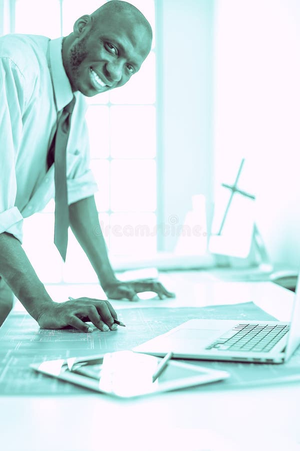 African American Architect Working With Computer And Blueprints In ...