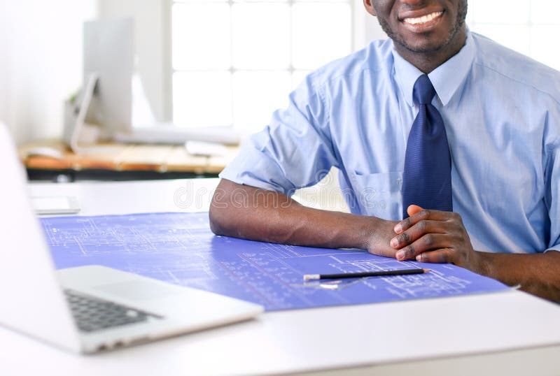 African American Architect Working with Computer and Blueprints in ...