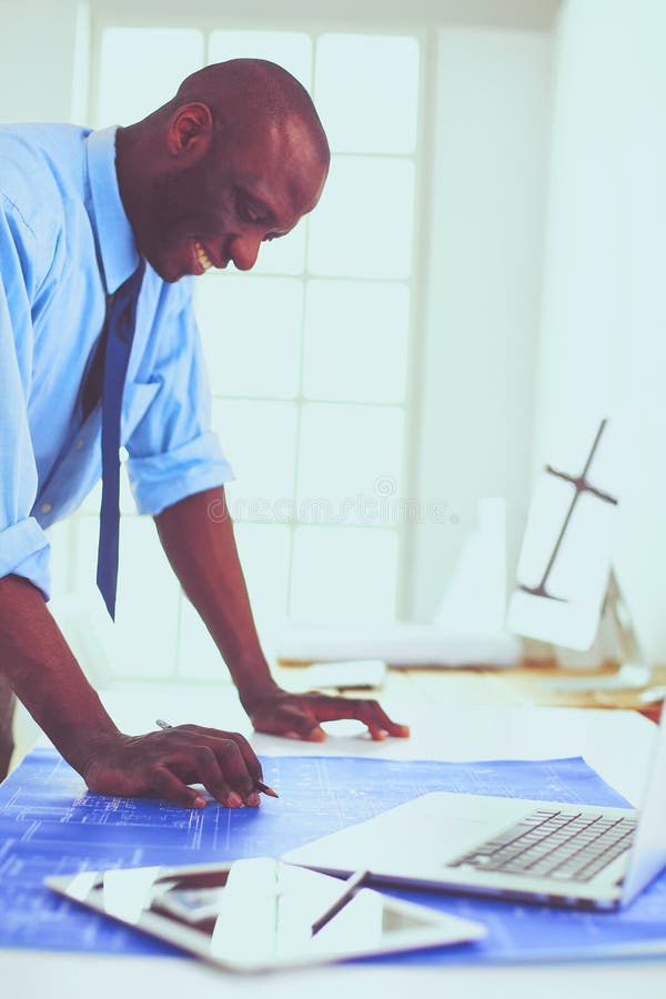 African American Architect Working with Computer and Blueprints in ...