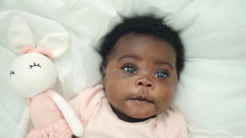 African American Baby Lying on Bed with Relaxed Expression at Bedroom ...