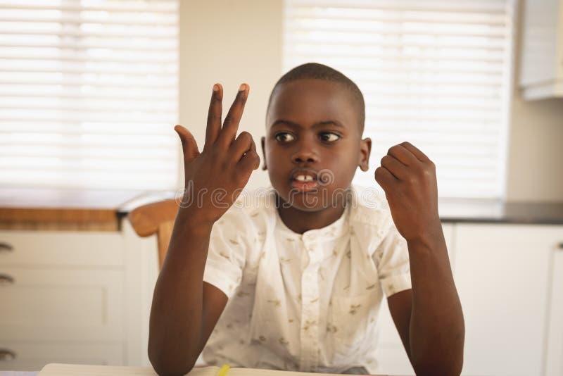 African American Boy Doing Homework on Dining Table in Kitchen Stock ...