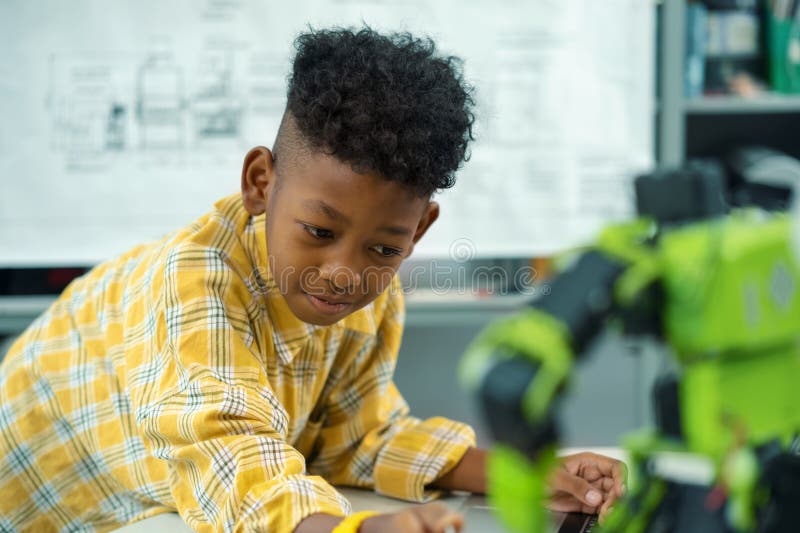 An African American Boy is Using Laptop Computer Programming Robot Kit ...