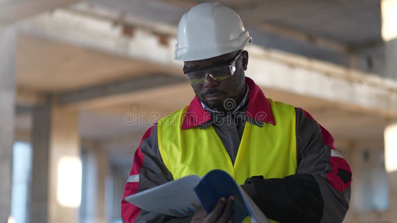 African American Builder Stands at Construction Site, Holds in Hands ...