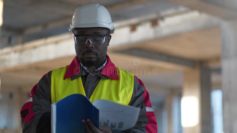 African American Builder Stands at Construction Site, Holds in Hands ...