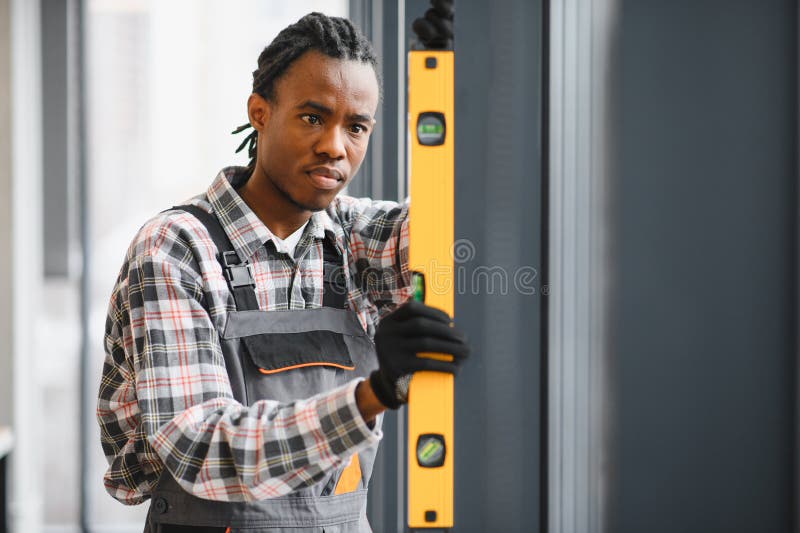 African American Construction Worker Checking Alignment of Window Frame ...