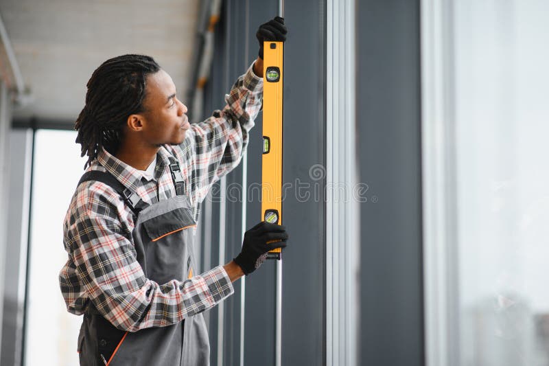 African American Construction Worker Checking Vertical Alignment with ...