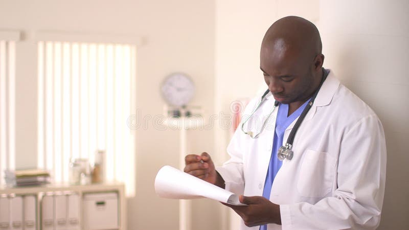 African American Doctor Smiling at Camera Then Resuming Work Stock ...
