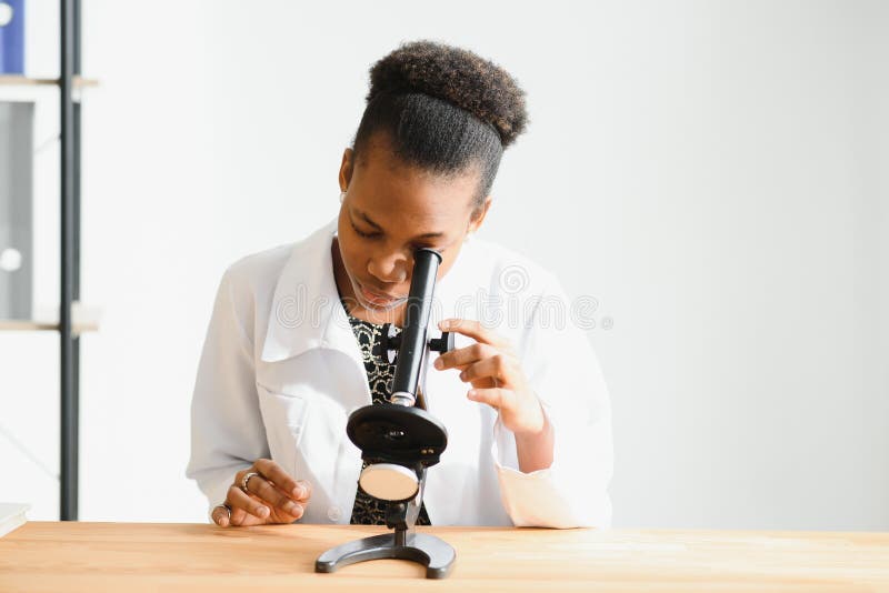 African American Female Lab Technician Looking through Microscope in ...
