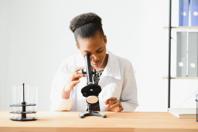 African American Female Lab Technician Looking through Microscope in ...
