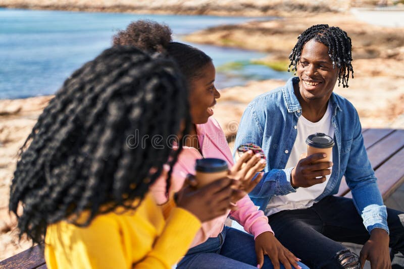 African American Friends Having Breakfast Sitting on Bench at Seaside ...