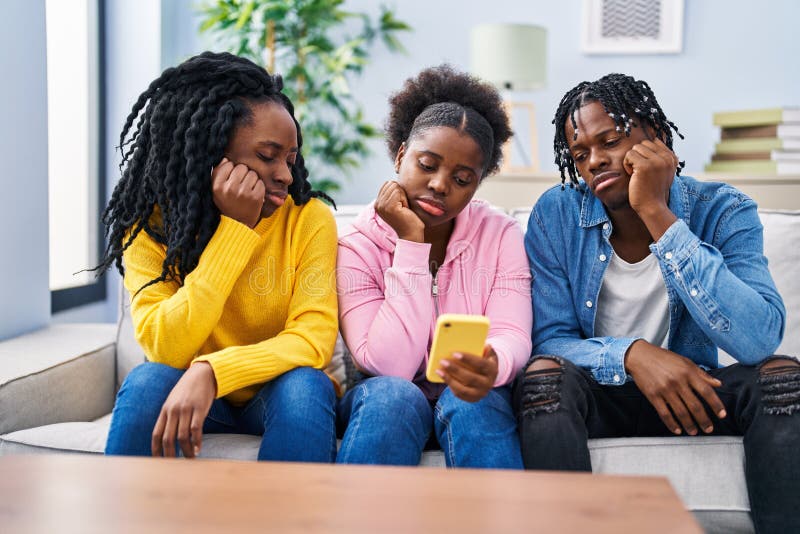African American Friends Using Smartphone Sitting on Sofa at Home Stock ...