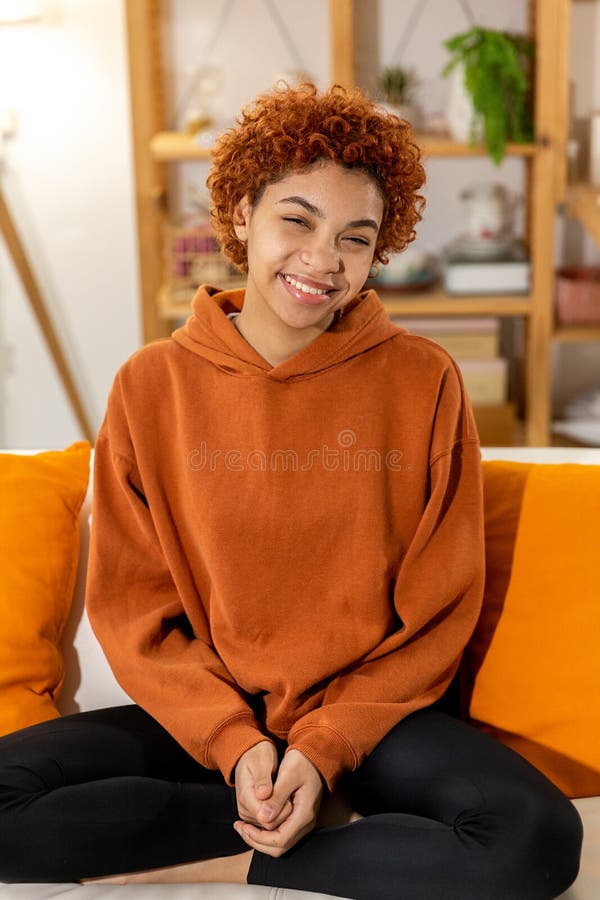 African American Girl With Afro Hairstyle Smiling Sitting On Sofa At