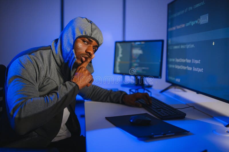 African American Hacker with Computer, Man Sitting at a Table in a ...