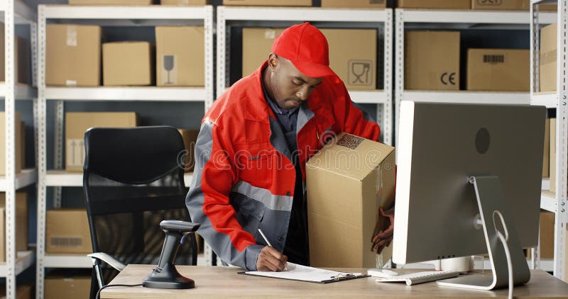 African American Mailman in Uniform Working at Computer in Post Office ...