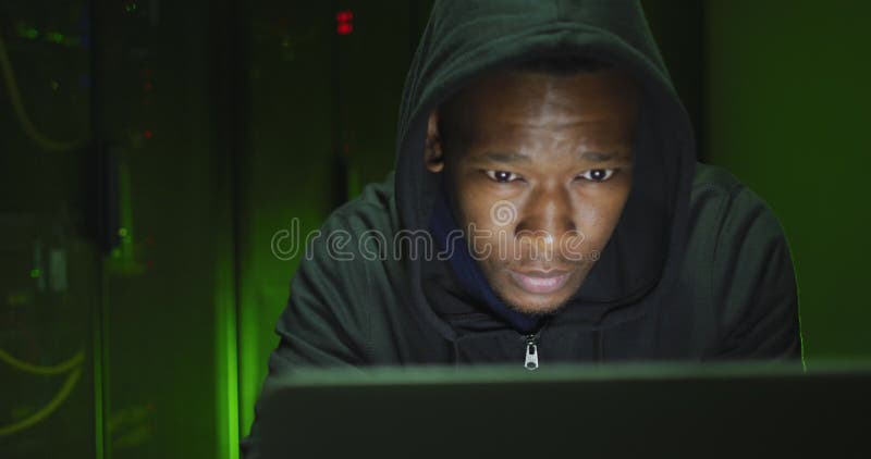 African American Male Computer Hacker Using Laptop in Business Server ...