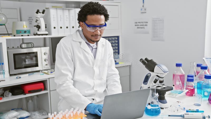 African American Male Scientist Analyzing Data on Laptop in Laboratory ...