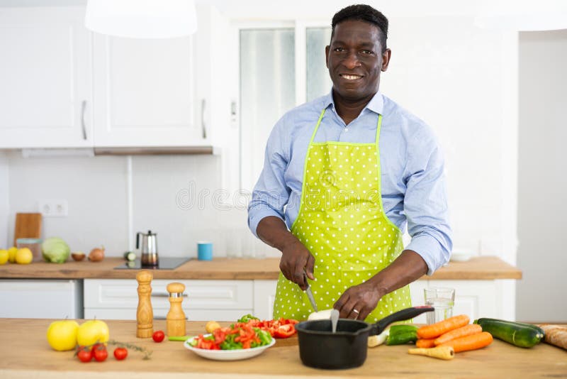 African American Man in an Apron Cooks Cuts Vegetables for Making Soup ...