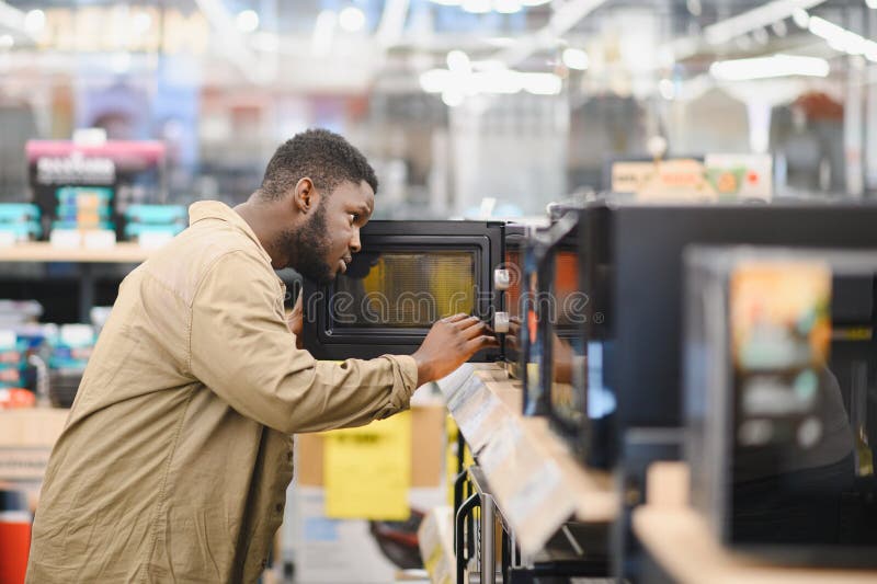 An African-American Man is Choosing a New Microwave Oven at an ...