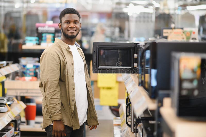 An African-American Man is Choosing a New Microwave Oven at an ...
